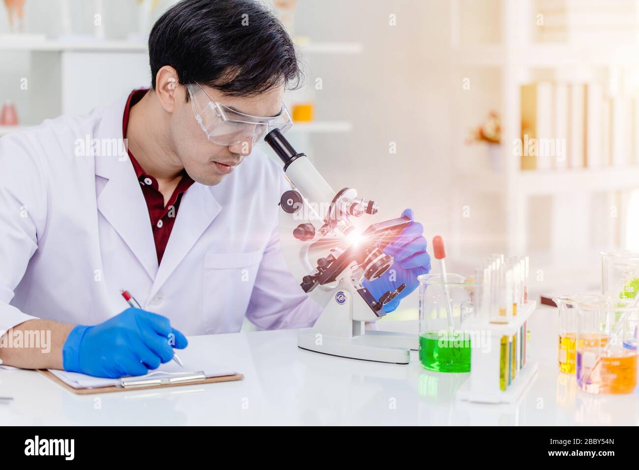 Scientist looking at microscope or Doctor pay attention working in lab ...