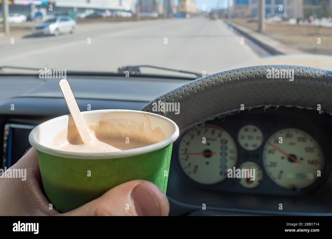 view of a glass of cocoa, chocolate, hot drink in the hand of a driver ...