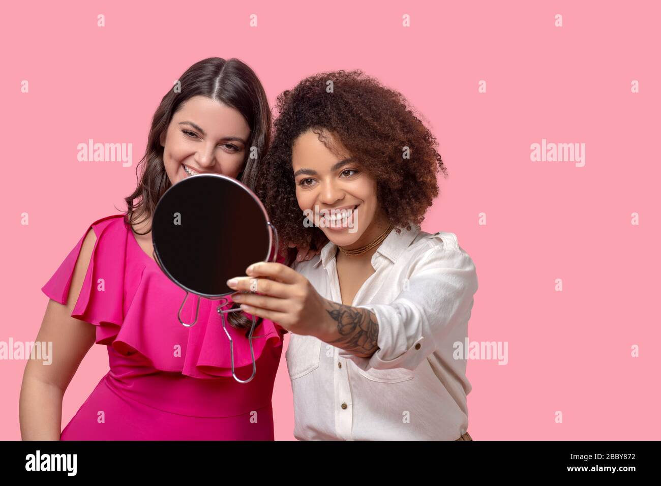 Two girlfriend looking at the mirror with pleasure Stock Photo - Alamy
