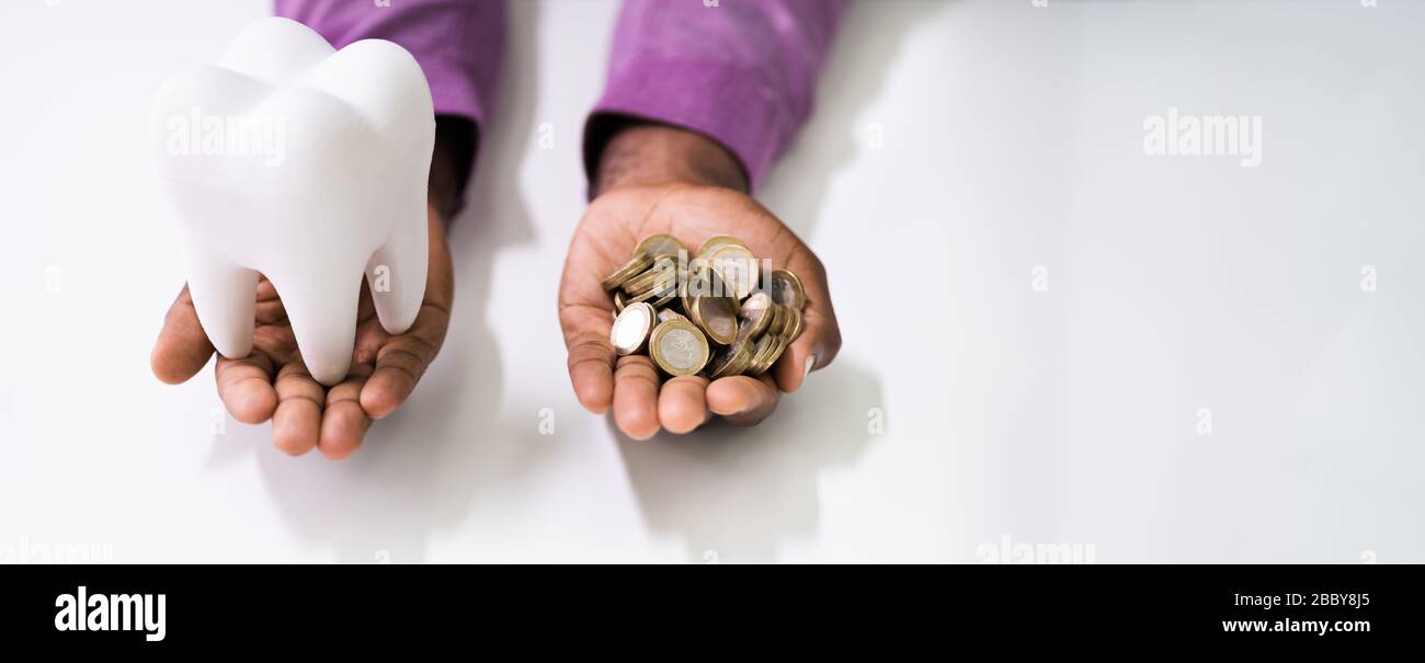 Close-up Of A Man's Hand Holding White Tooth And Golden Coins Over Desk ...