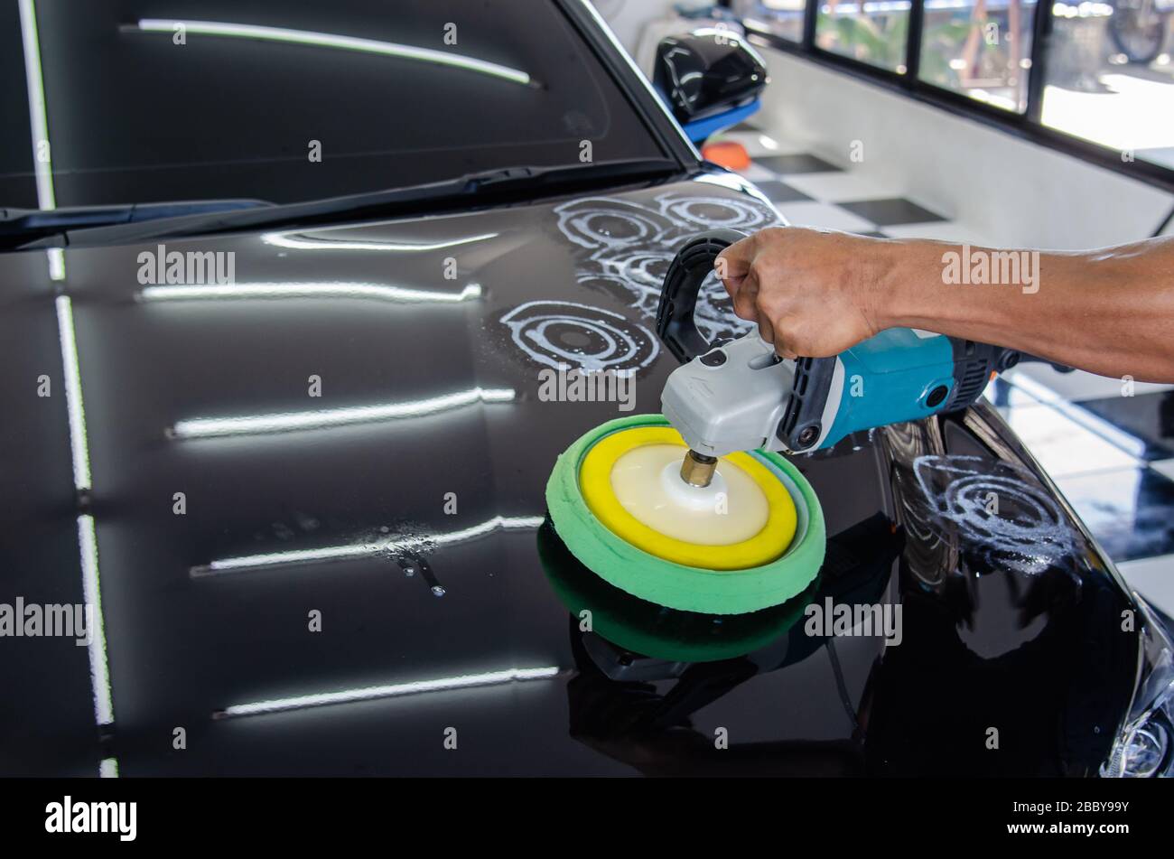 Car detailing - Car care service. Man holding a polisher in his hand ...