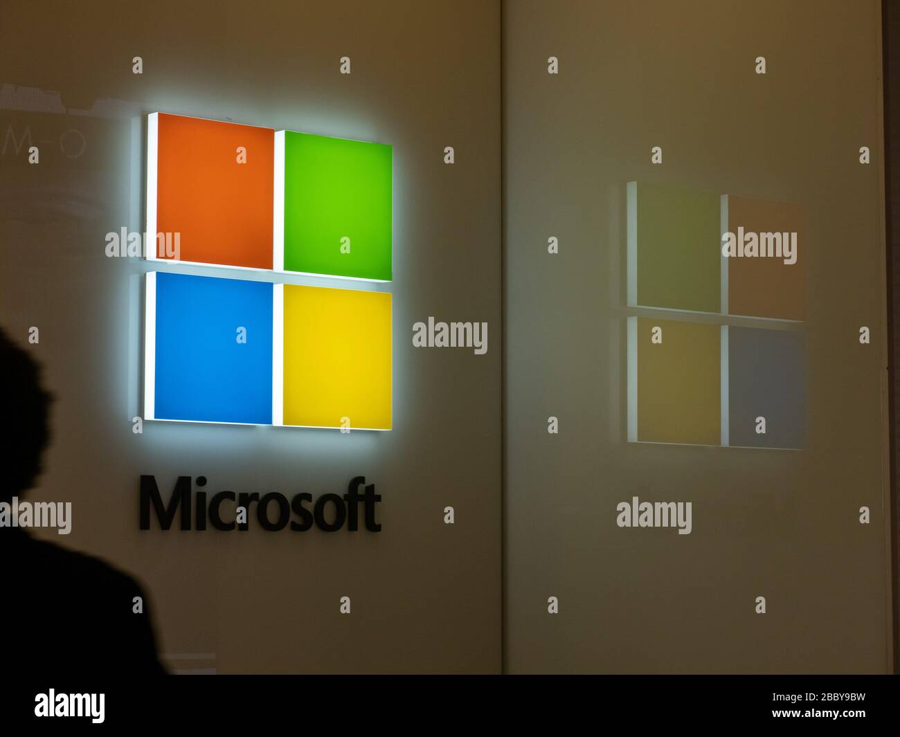 Microsoft logo and reflect with man walking by in shadow Stock Photo ...