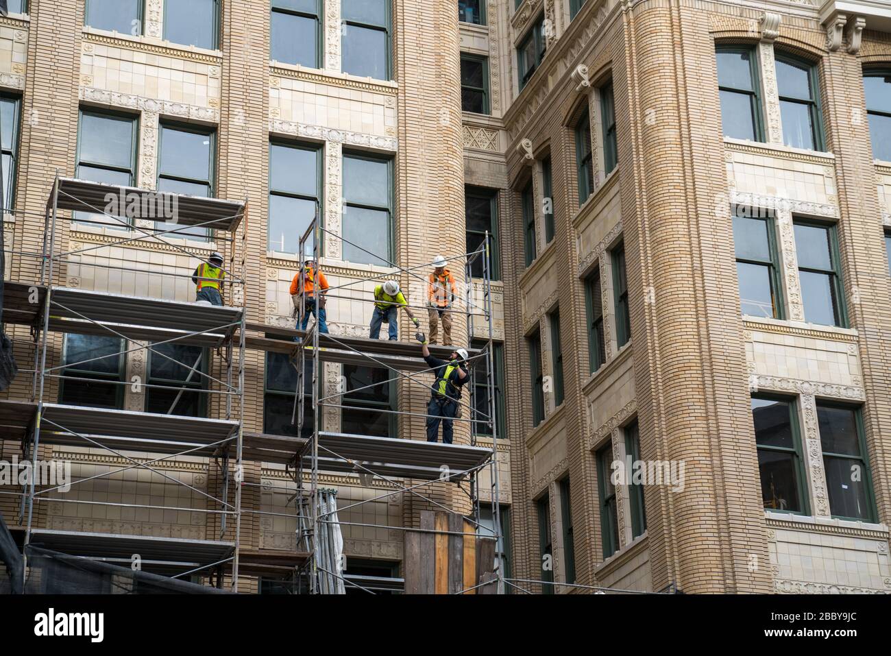 Construction crew on scaffolding repairing outside of building Stock ...