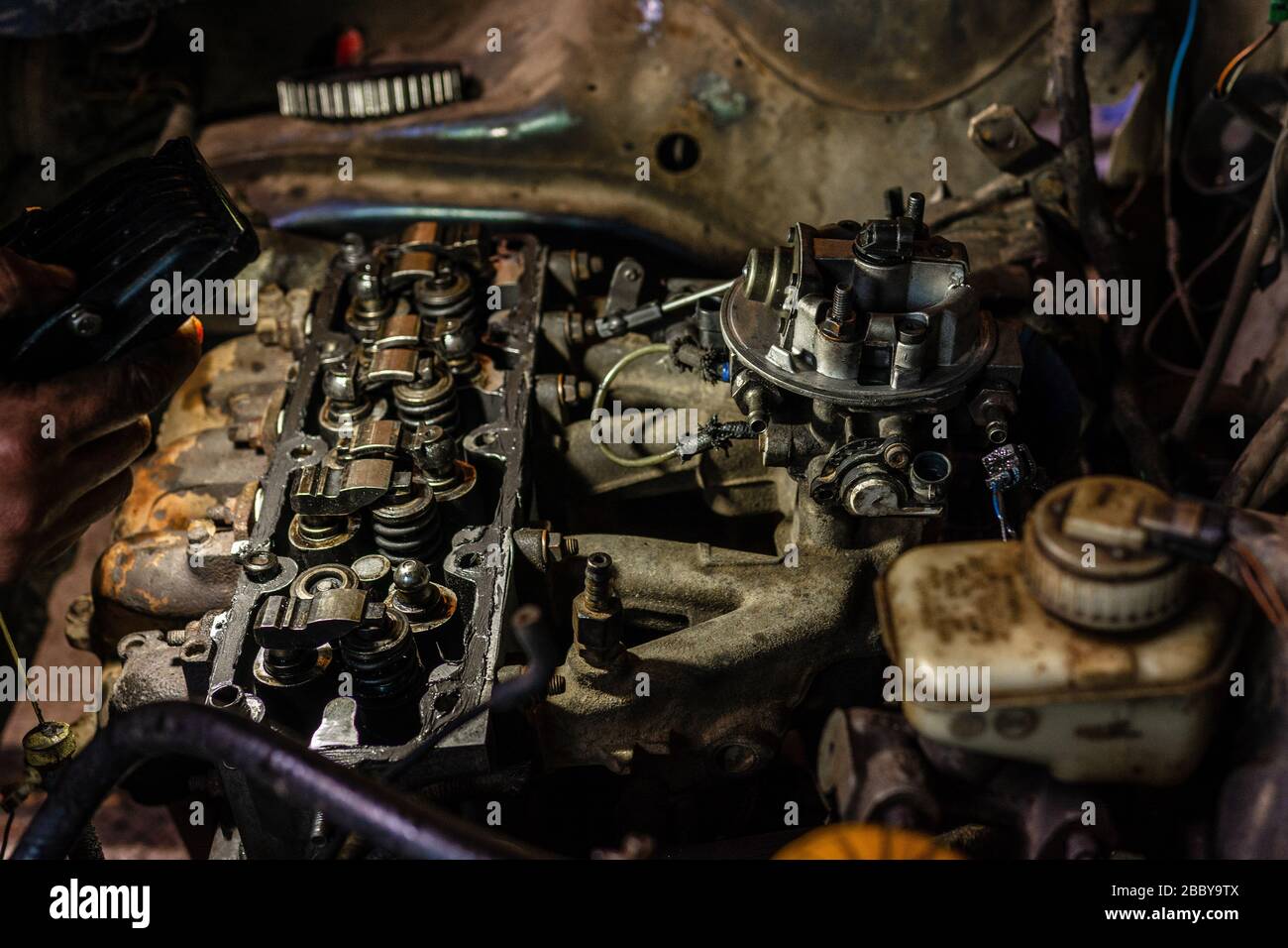 A mechanic shines a flashlight on a defective engine in a car service ...