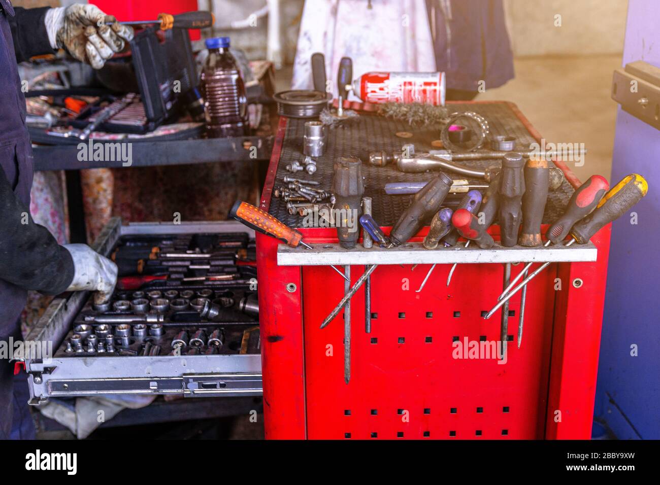 The mechanic in the car service picks up a tool for repairing the car ...