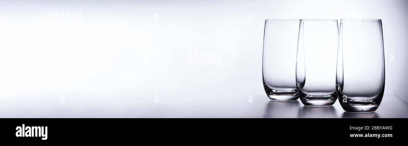 three empty glass glasses on a white background. Close up. long layout ...