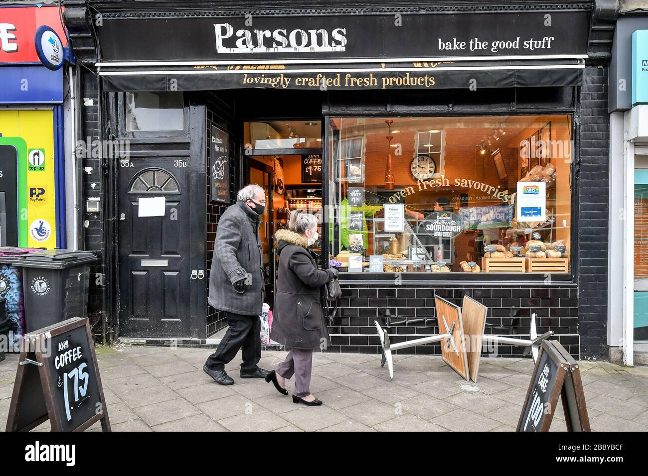 A couple wear face masks as they pass a bakery in Brislington, Bristol ...
