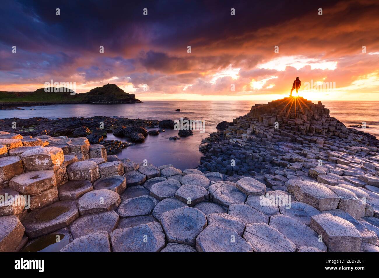 A man enjoying an epic sunset on the Giant's Causeway with it's iconic ...