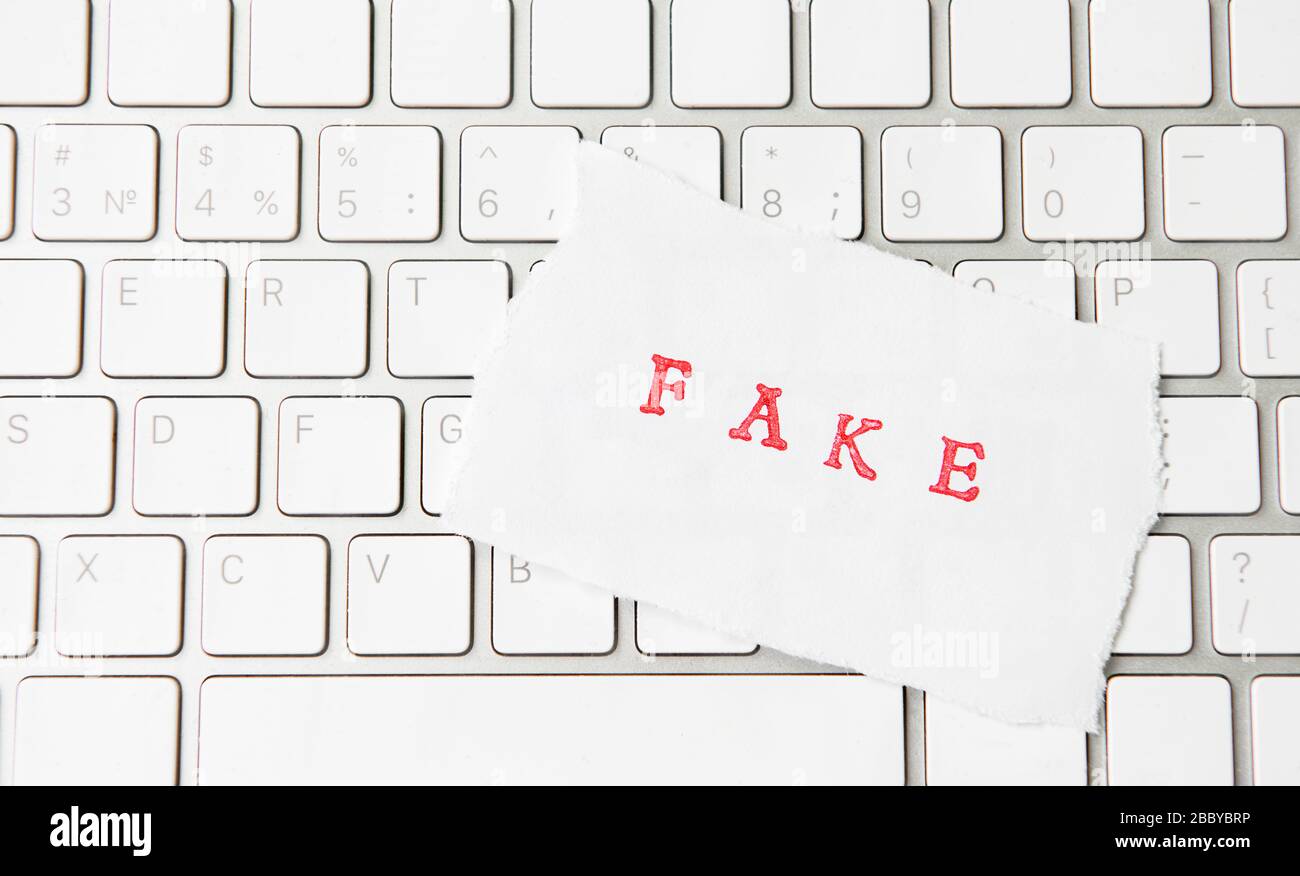 Word Fake written on torn paper on a computer keyboard Stock Photo - Alamy