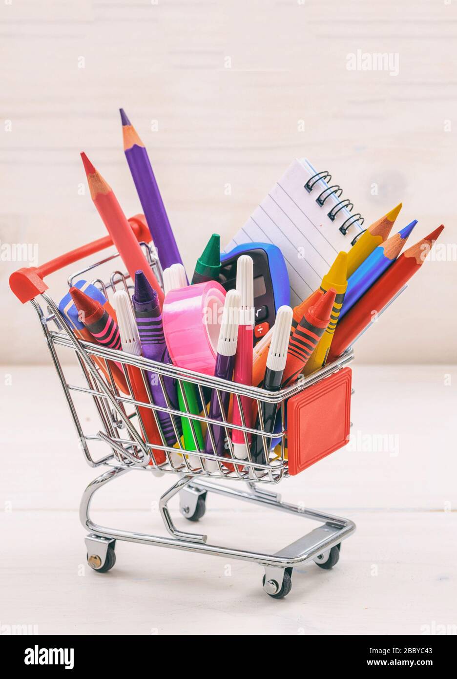 School supplies in a shopping cart, natural wood background. Back to ...