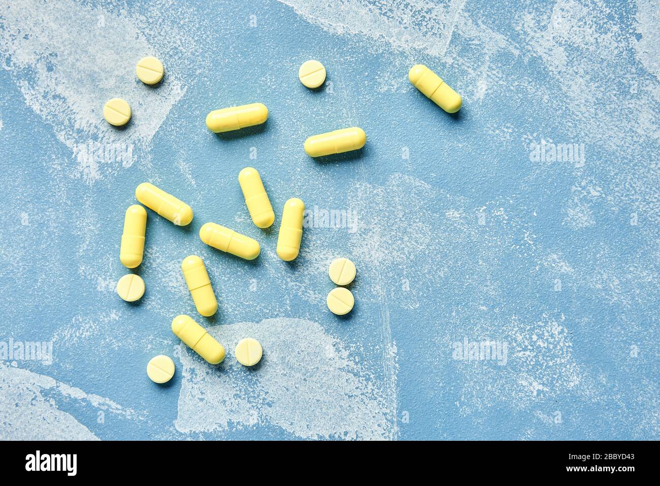 yellow pills on a blue background. view from above Stock Photo - Alamy