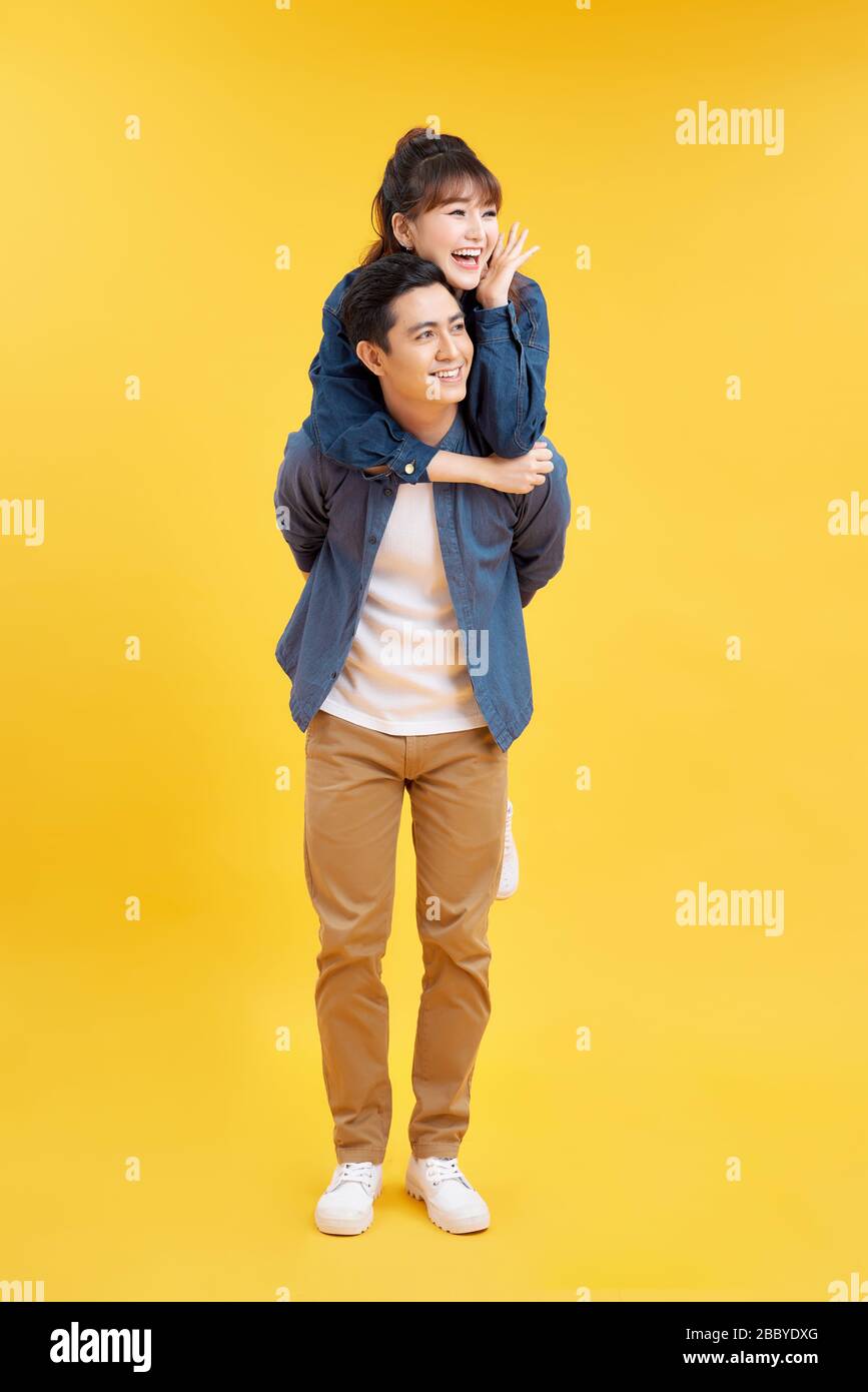 A beautiful young woman riding on the back of her handsome boyfriend ...