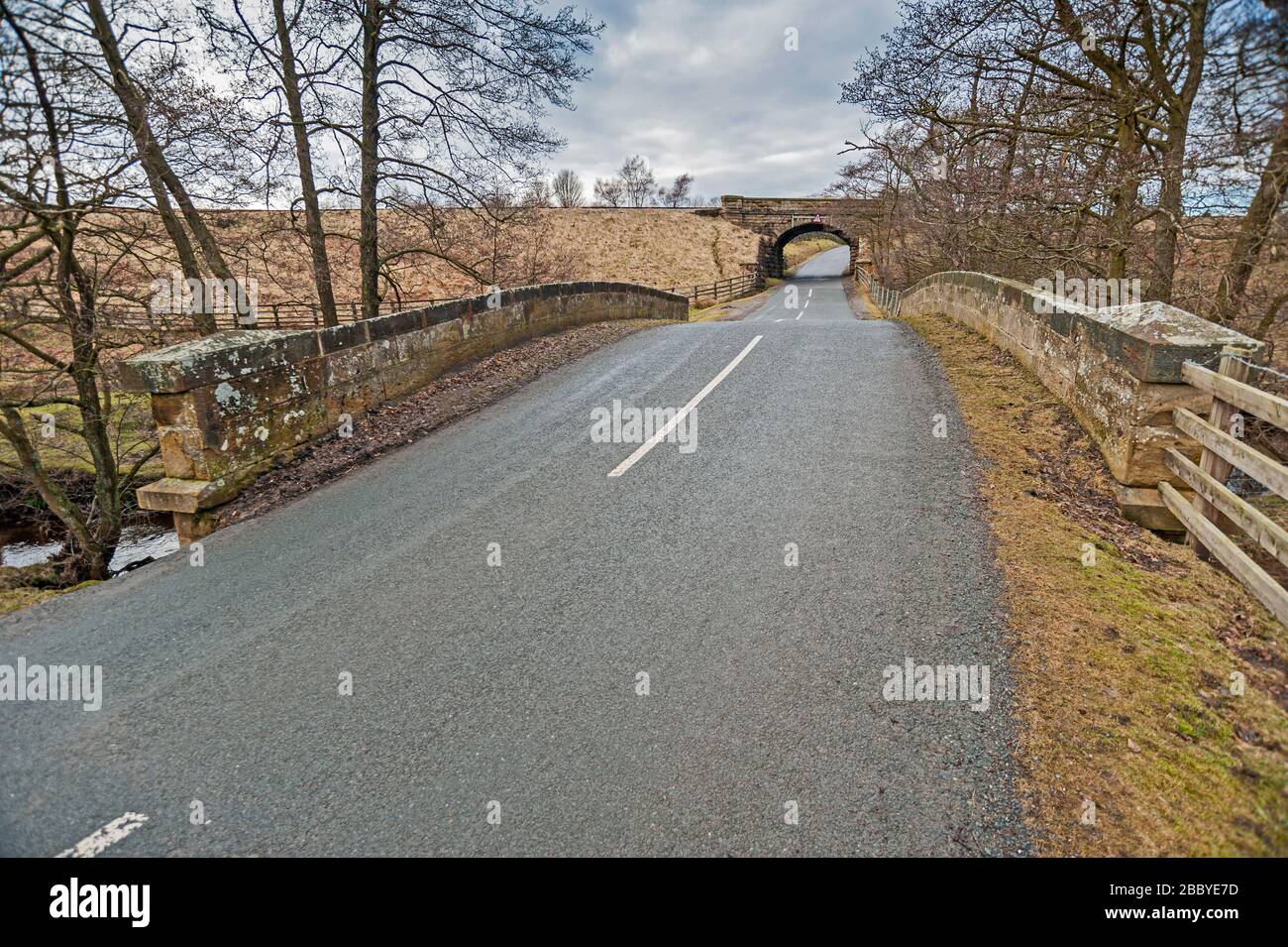 Road in rural countryside landscape over stone bridge heading towards ...