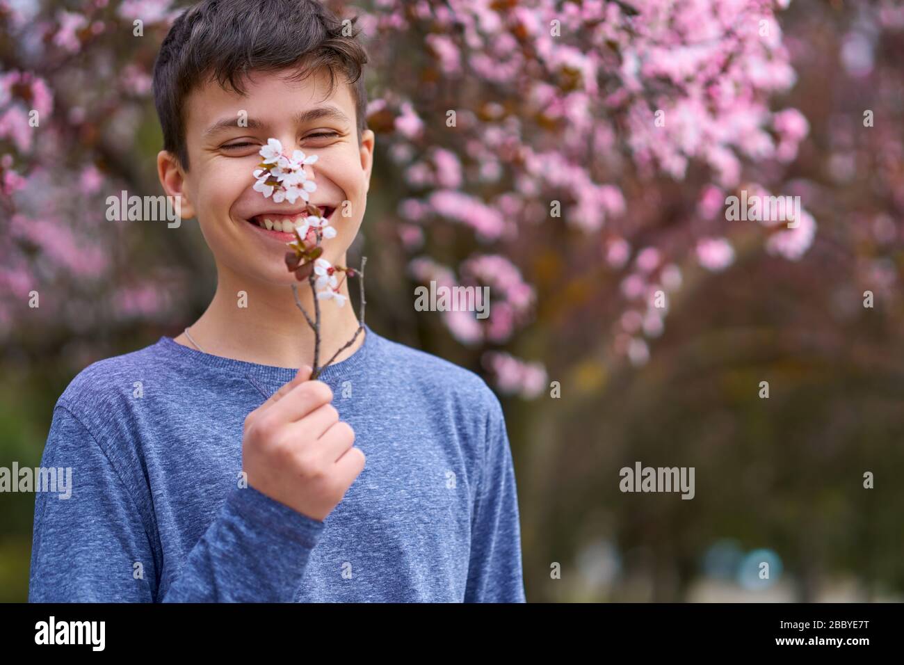 boy with a face mask is in the city outdoor, blooming trees, spring season, flowering time ...