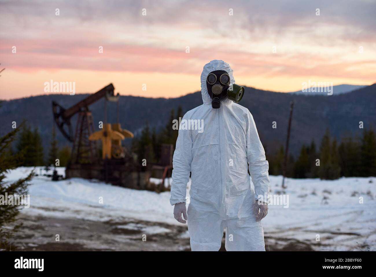 Scientist wearing white coverall, gloves and a gas mask working in oil ...