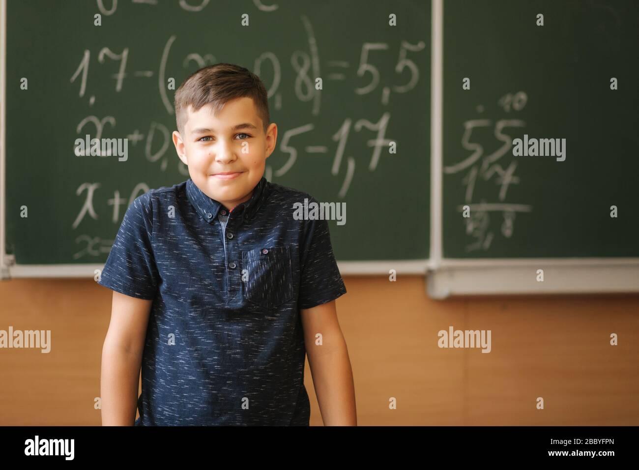 Cute boy stand in the classroom background of blackboard. Education ...