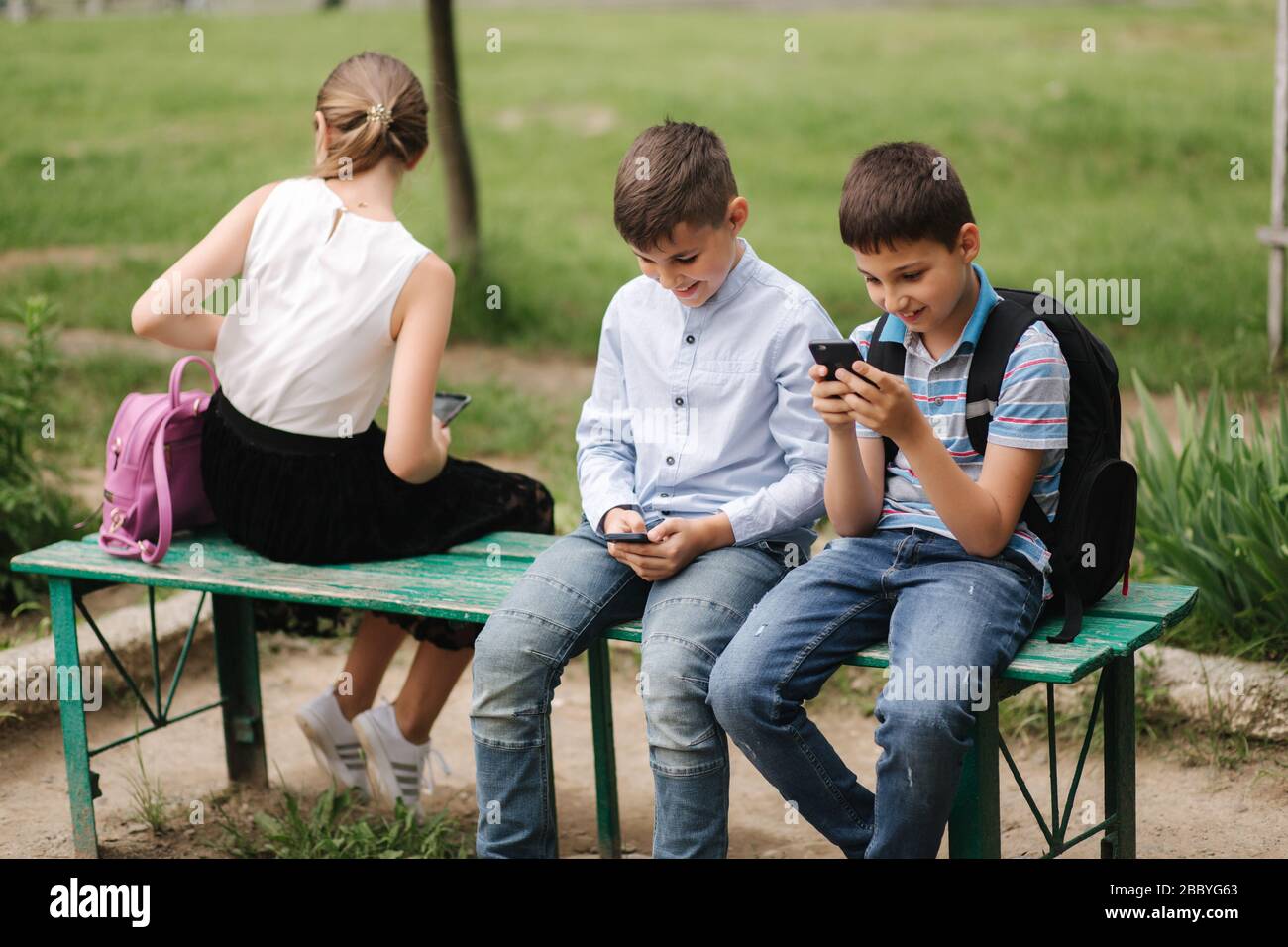 Two boys and girl use their phones during school breack. Cute boys ...