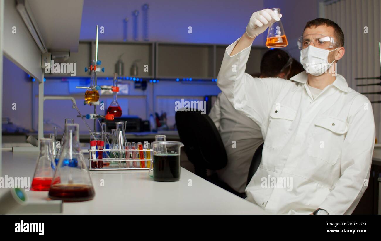 Young scientist mixing colored liquids in a flask Stock Photo - Alamy