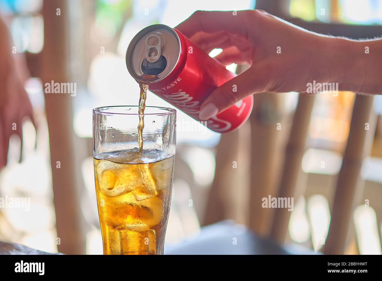A glass of rum and coke next to a red iron can of Coca Cola against the ...