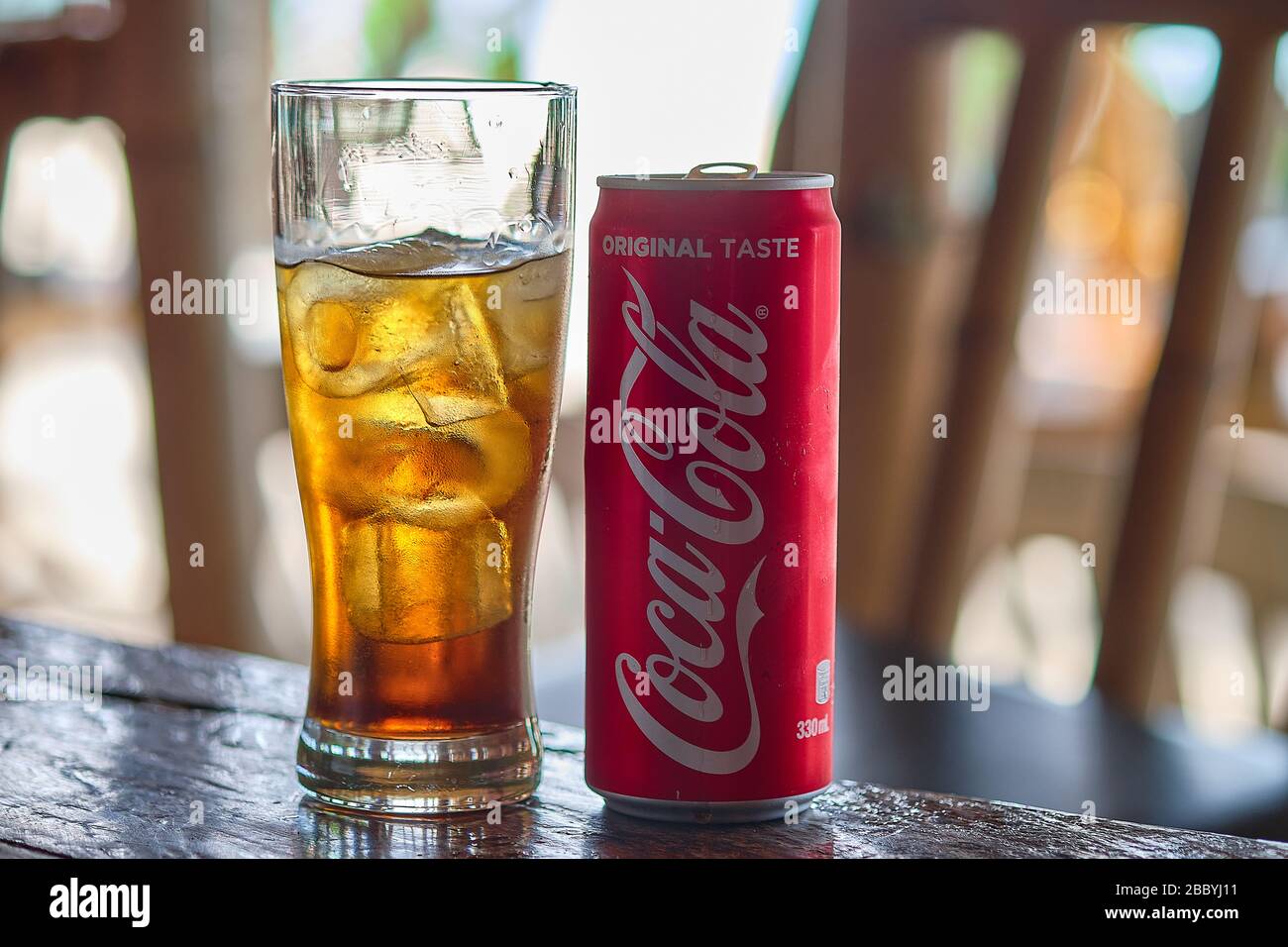 A glass of rum and coke next to a red iron can of Coca Cola against the ...