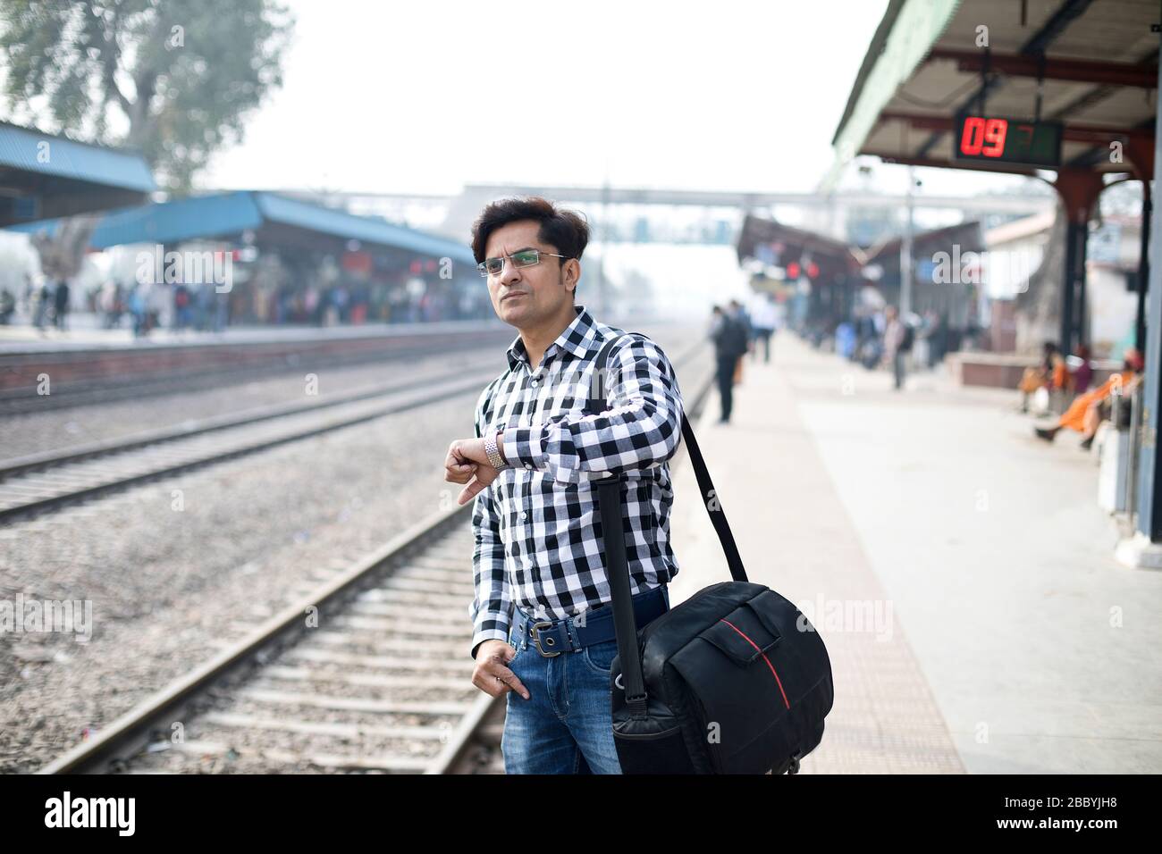 Man checking time while waiting at railway station Stock Photo - Alamy