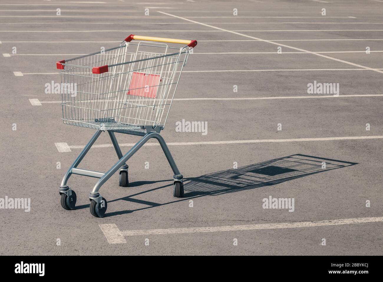 Empty grocery cart in an empty parking lot near a supermarket ...