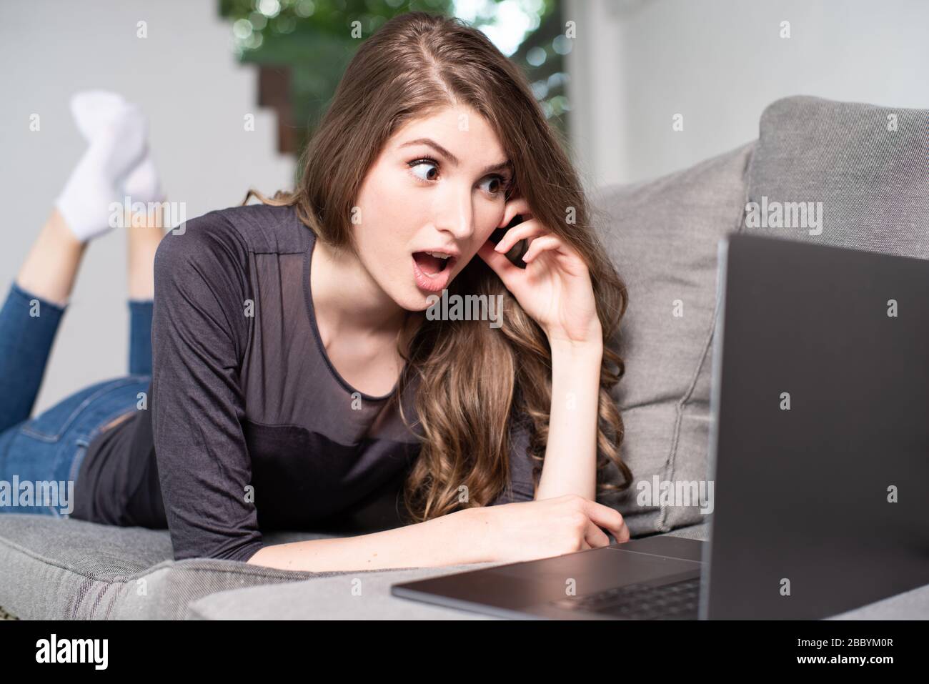 Young woman scared in front of laptop at home Stock Photo - Alamy