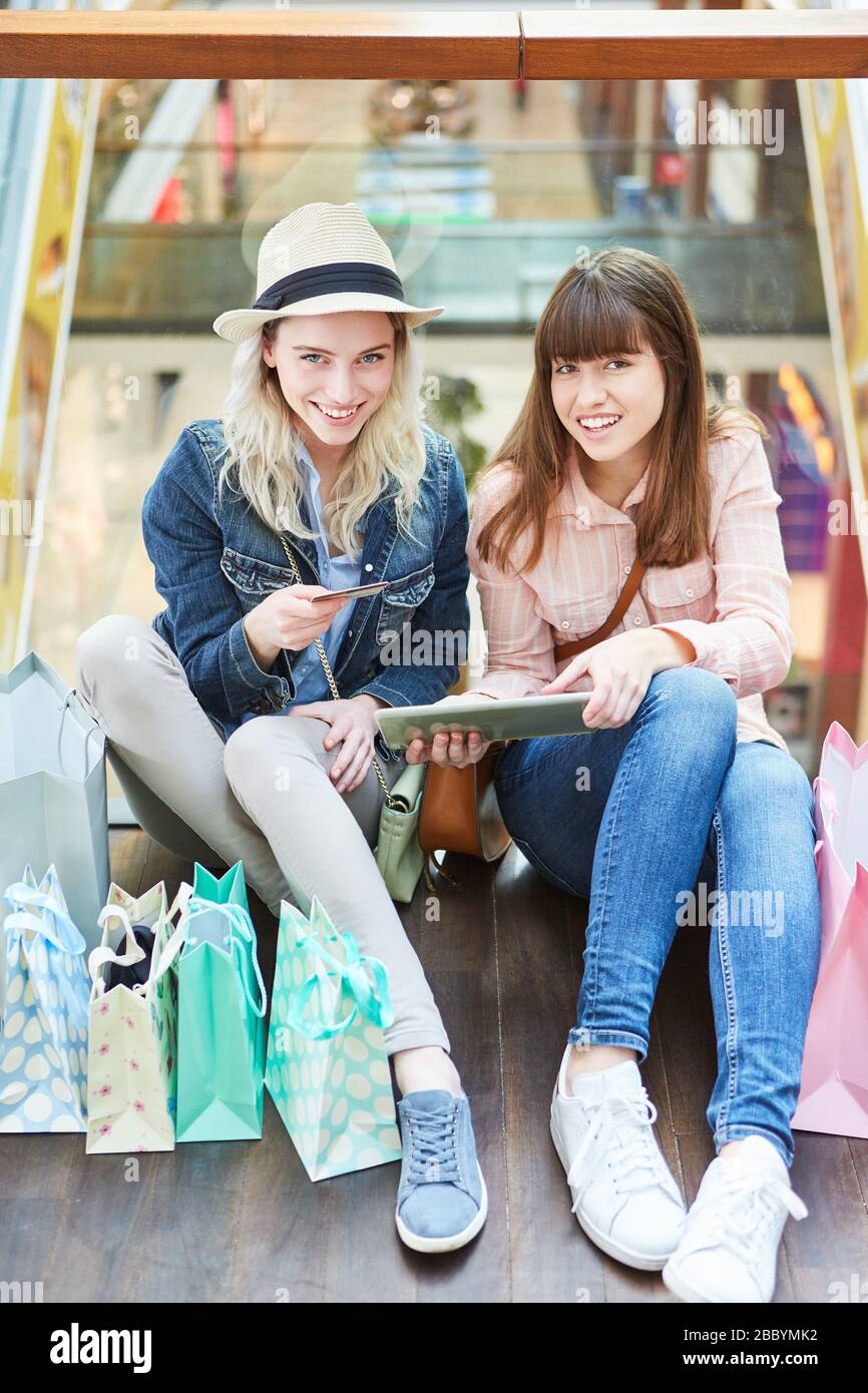 Two teenagers using credit card and tablet computer while shopping ...