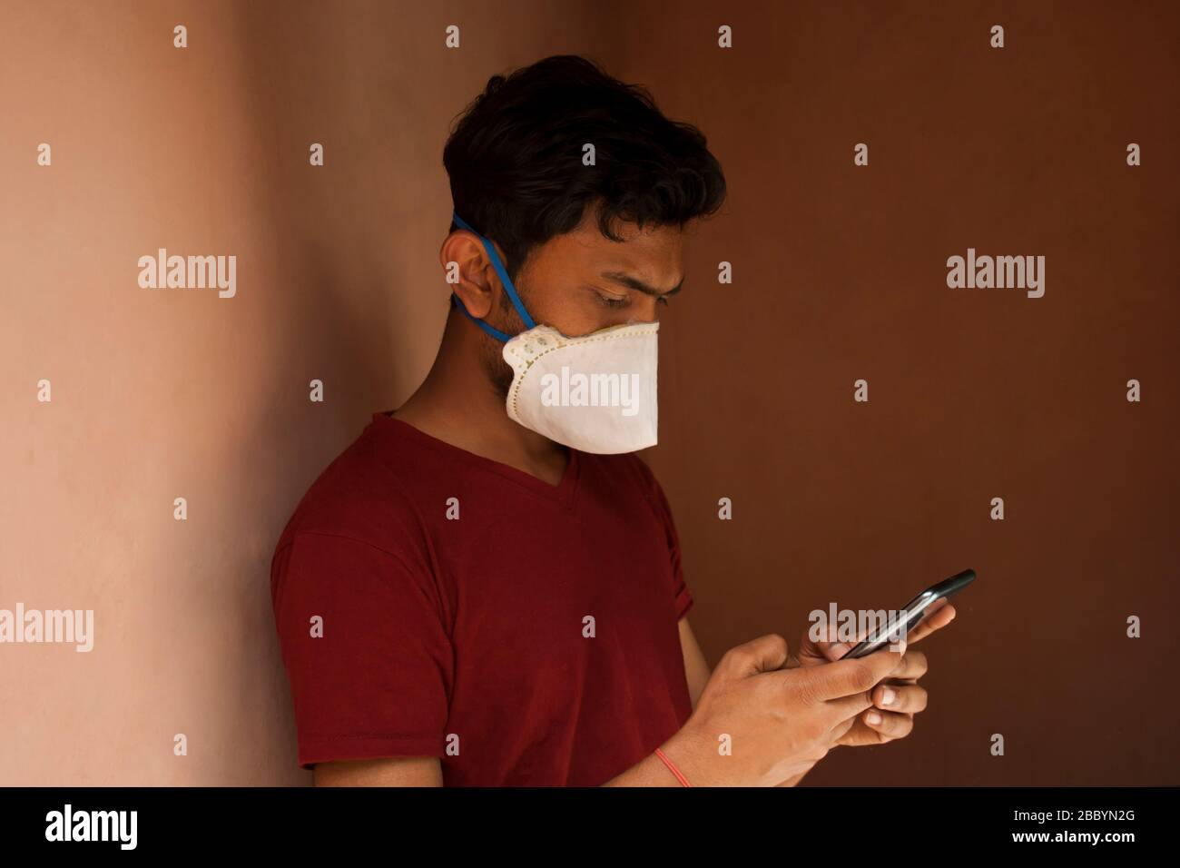 A Boy wearing a respiratory mask uses a mobile phone Stock Photo - Alamy