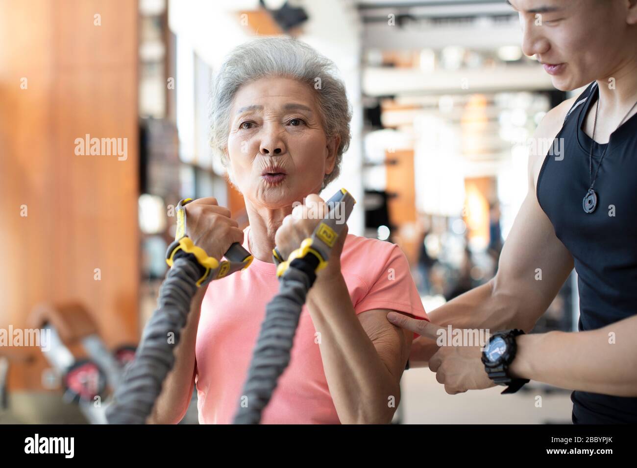 Senior Chinese woman working out with personal trainer at gym Stock ...