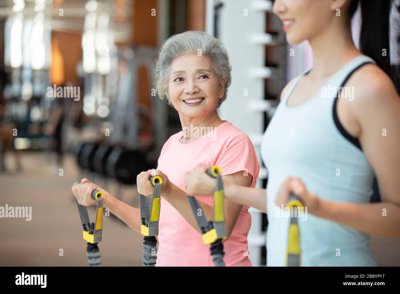 Senior Chinese woman working out with personal trainer at gym Stock ...