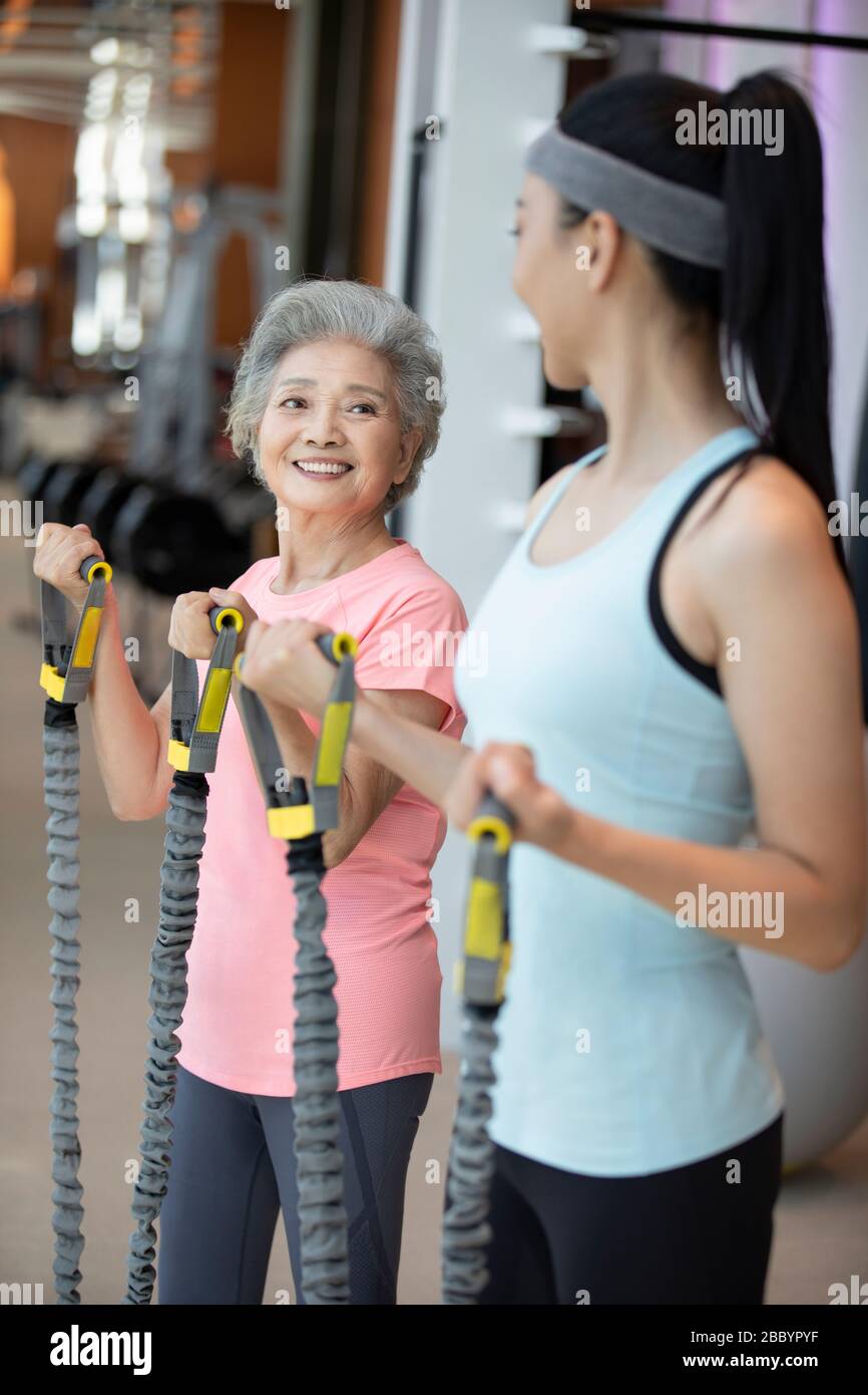 Senior Chinese woman working out with personal trainer at gym Stock ...