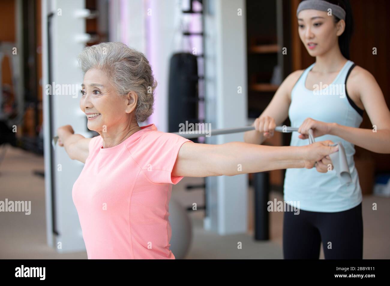 Senior Chinese woman working out with personal trainer at gym Stock ...