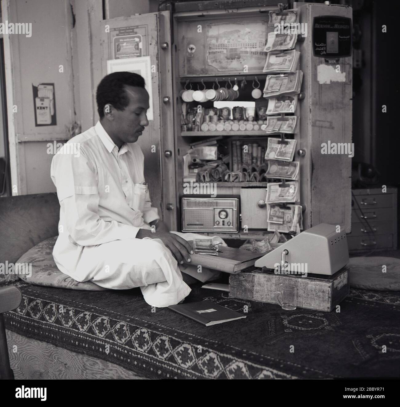 1960s, historical, street money exchange, a man sitting on a cushion on ...