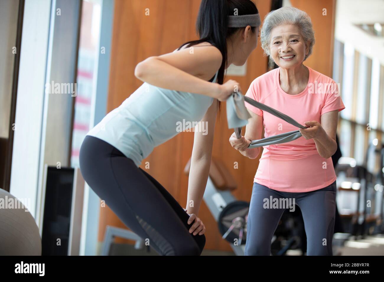 Senior Chinese woman working out with personal trainer at gym Stock ...