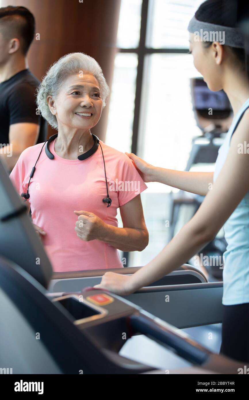 Senior Chinese woman working out with personal trainer at gym Stock ...