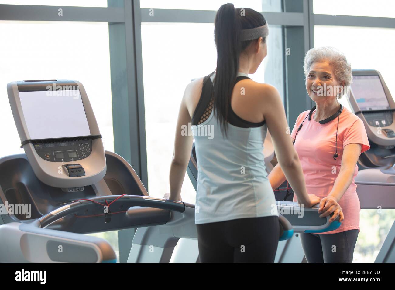 Senior Chinese woman working out with personal trainer at gym Stock ...