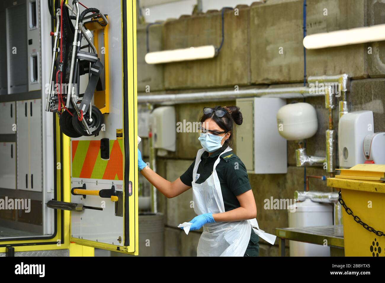 A paramedic cleans down equipment in the ambulance decontamination area ...