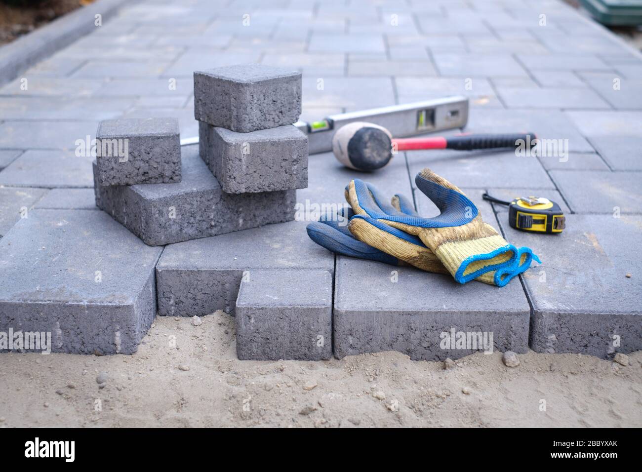 Paving stones pathway paving background. Installing tools on foreground ...