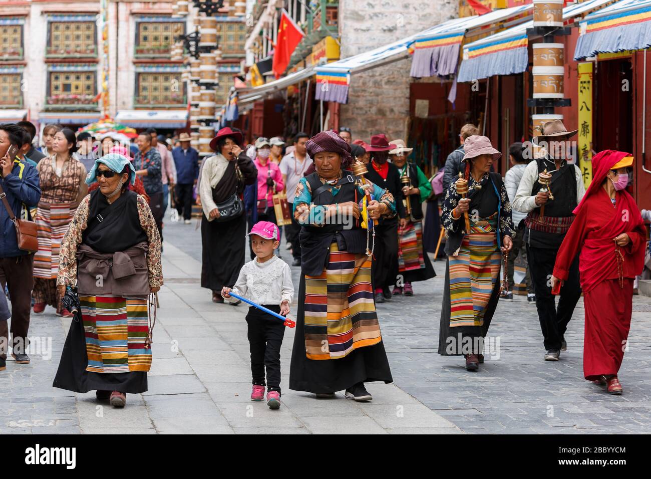 A group tibetan pilgrims walking on Barkhor street. They are holding ...