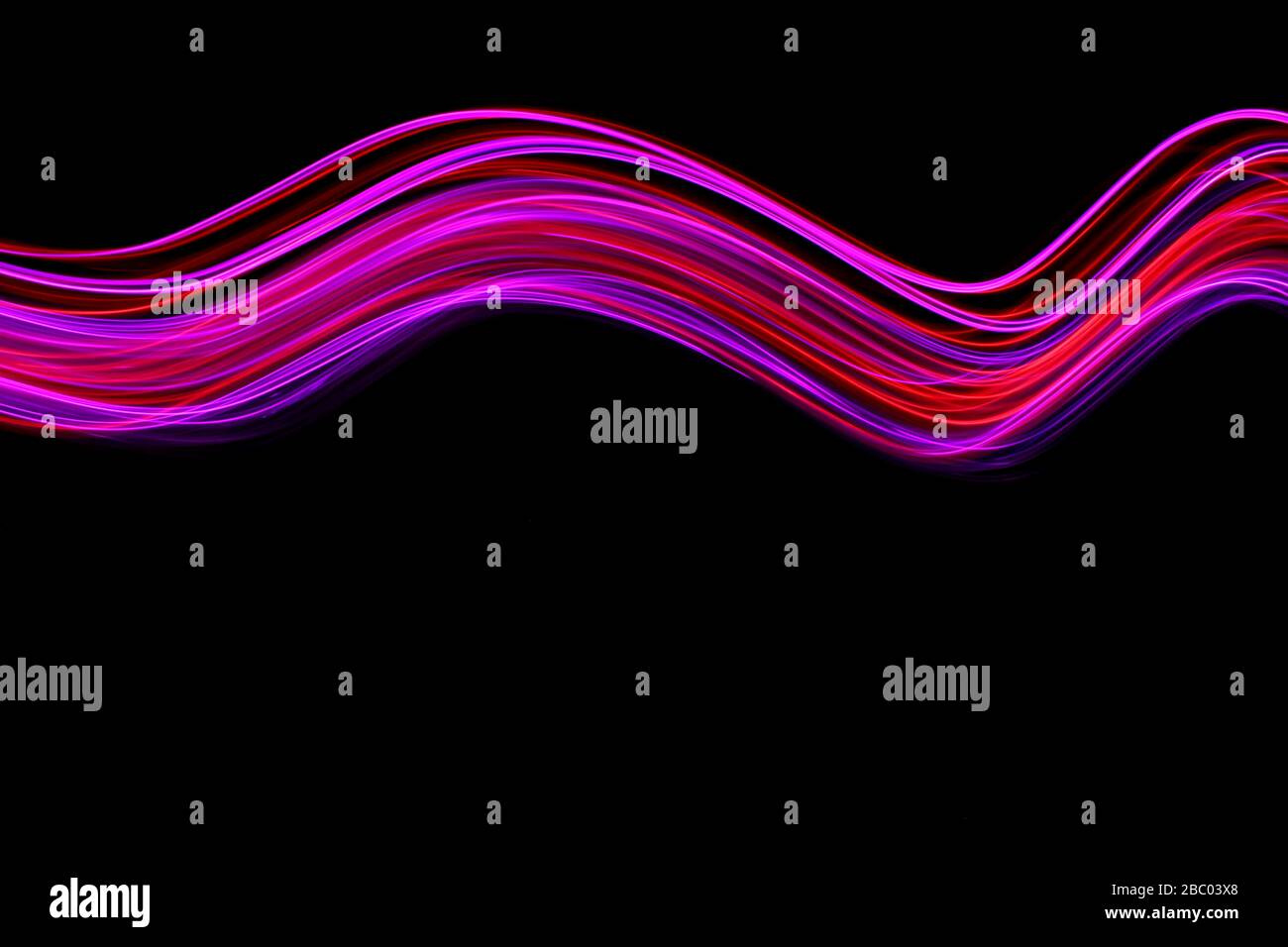 Long exposure photograph of neon pink/red colour in an abstract swirl ...