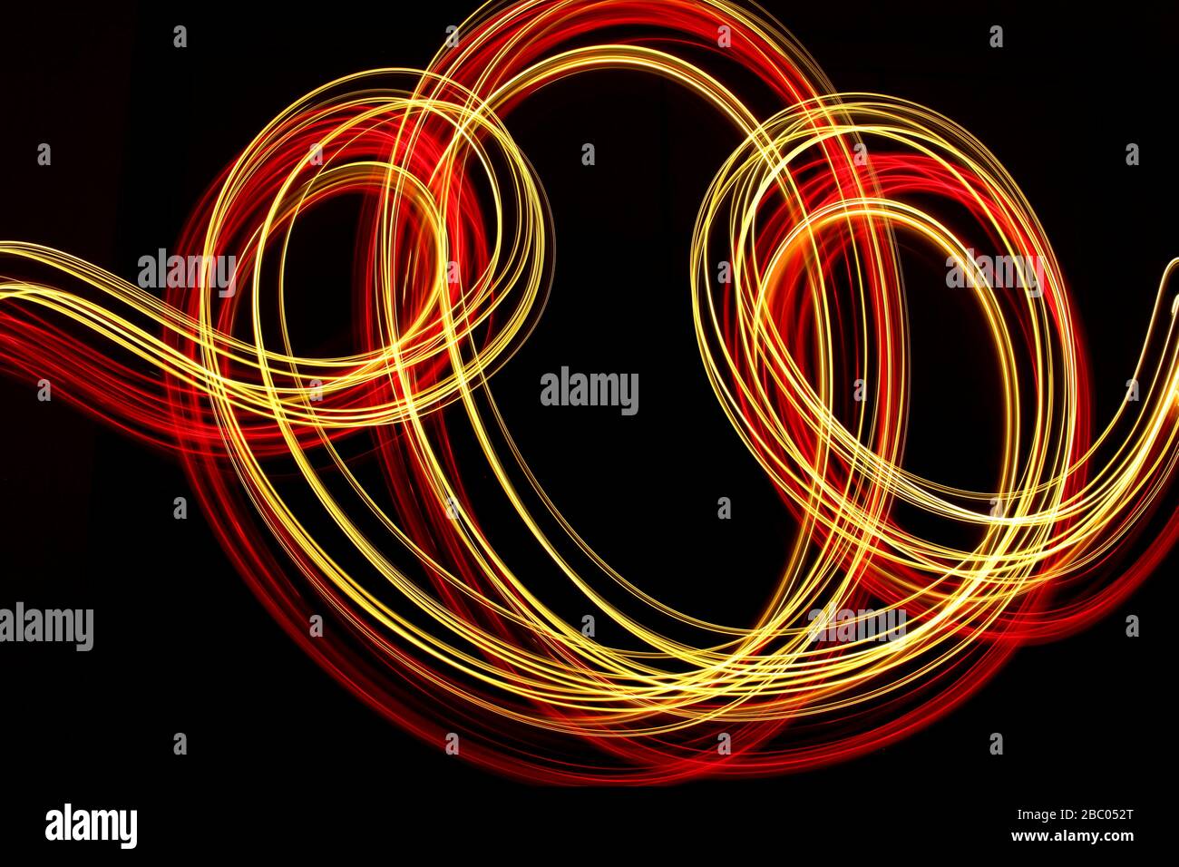 Long exposure photo of neon red and gold colour in an abstract swirl ...