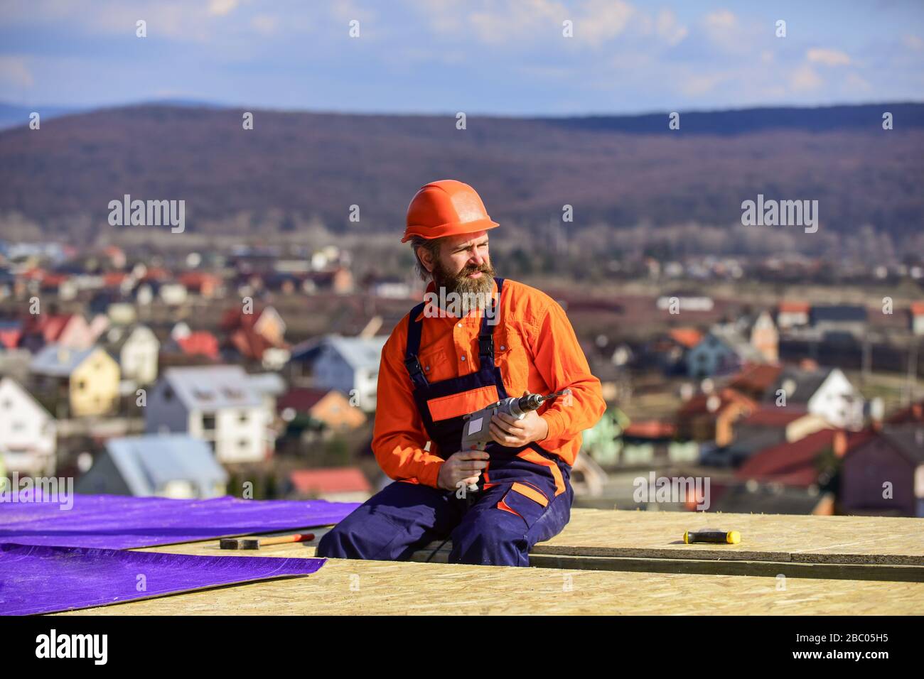 Roofer constructing roof. Man roofing surface. Install partially ...