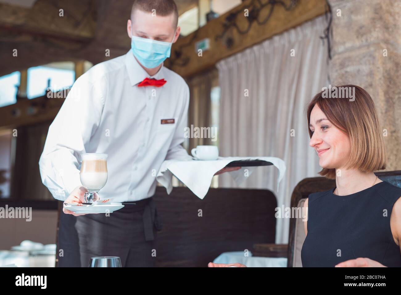the waiter works in a restaurant in a medical mask Stock Photo - Alamy