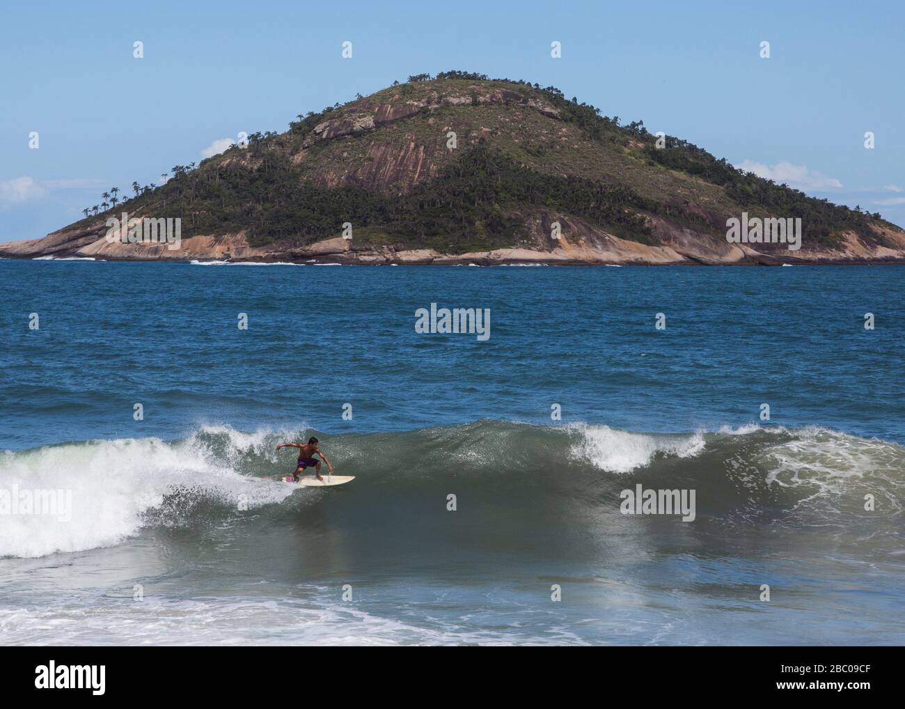 A Surfer surf's the wave with an Island in the background on the ...