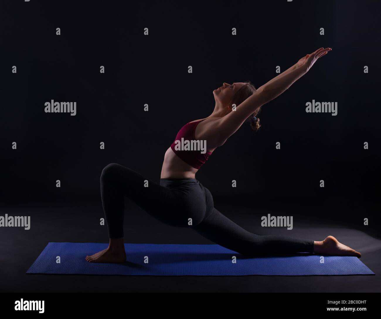 Photo of young sport woman doing yoga on mat over dark background Stock ...