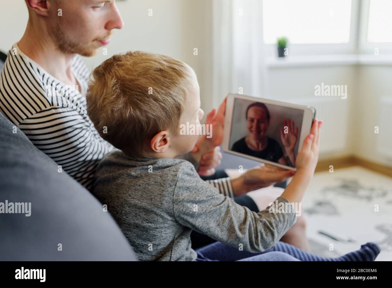 Father and son having video call to mother using tablet. Family ...