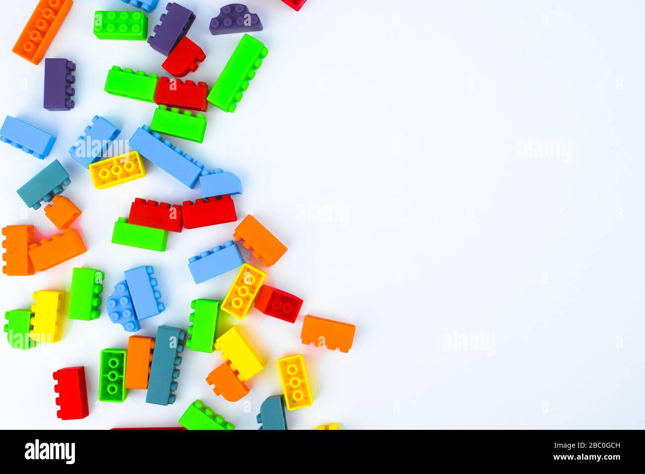 Different colored building blocks scattered across an empty white ...