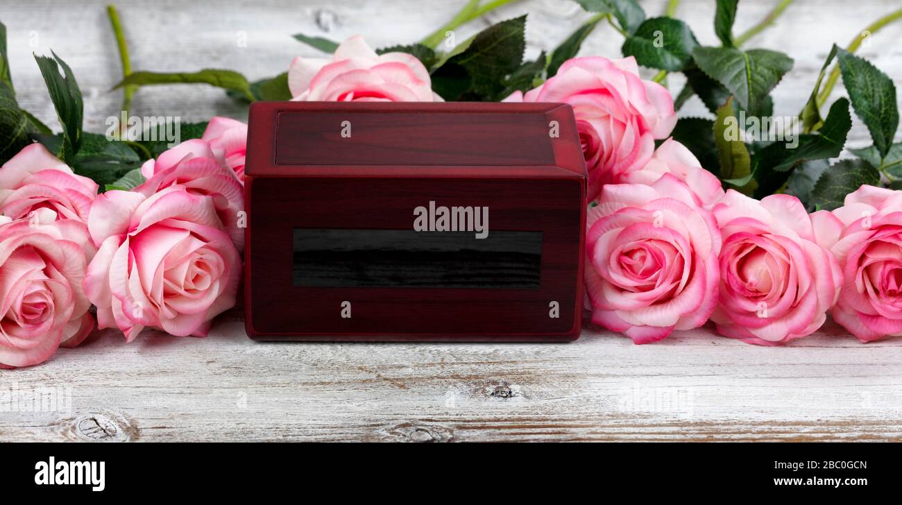 Close up of a cremation funeral box with rose flowers for death concept ...
