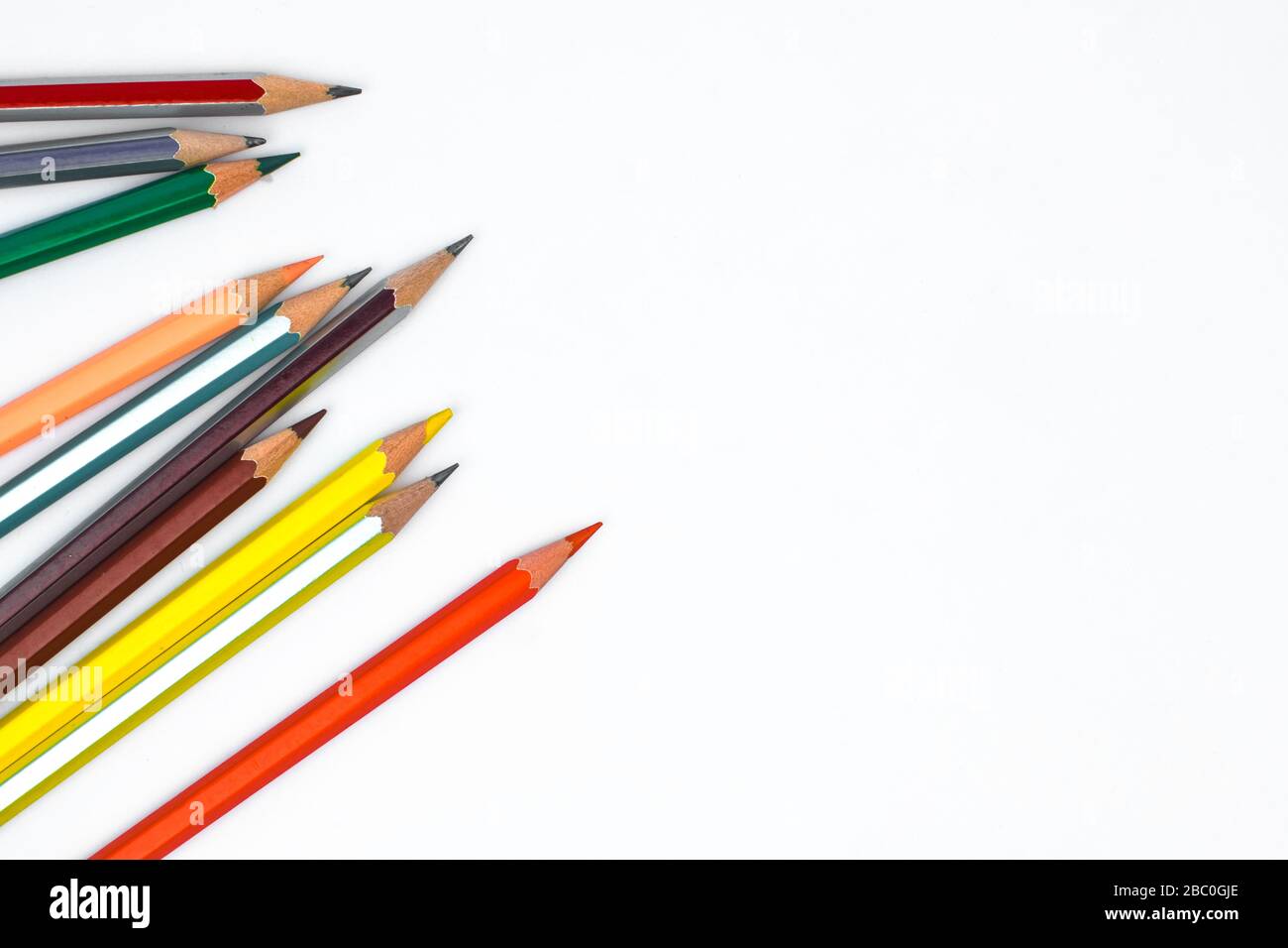 Scattered row of various colored wood pencil crayons arranged together ...